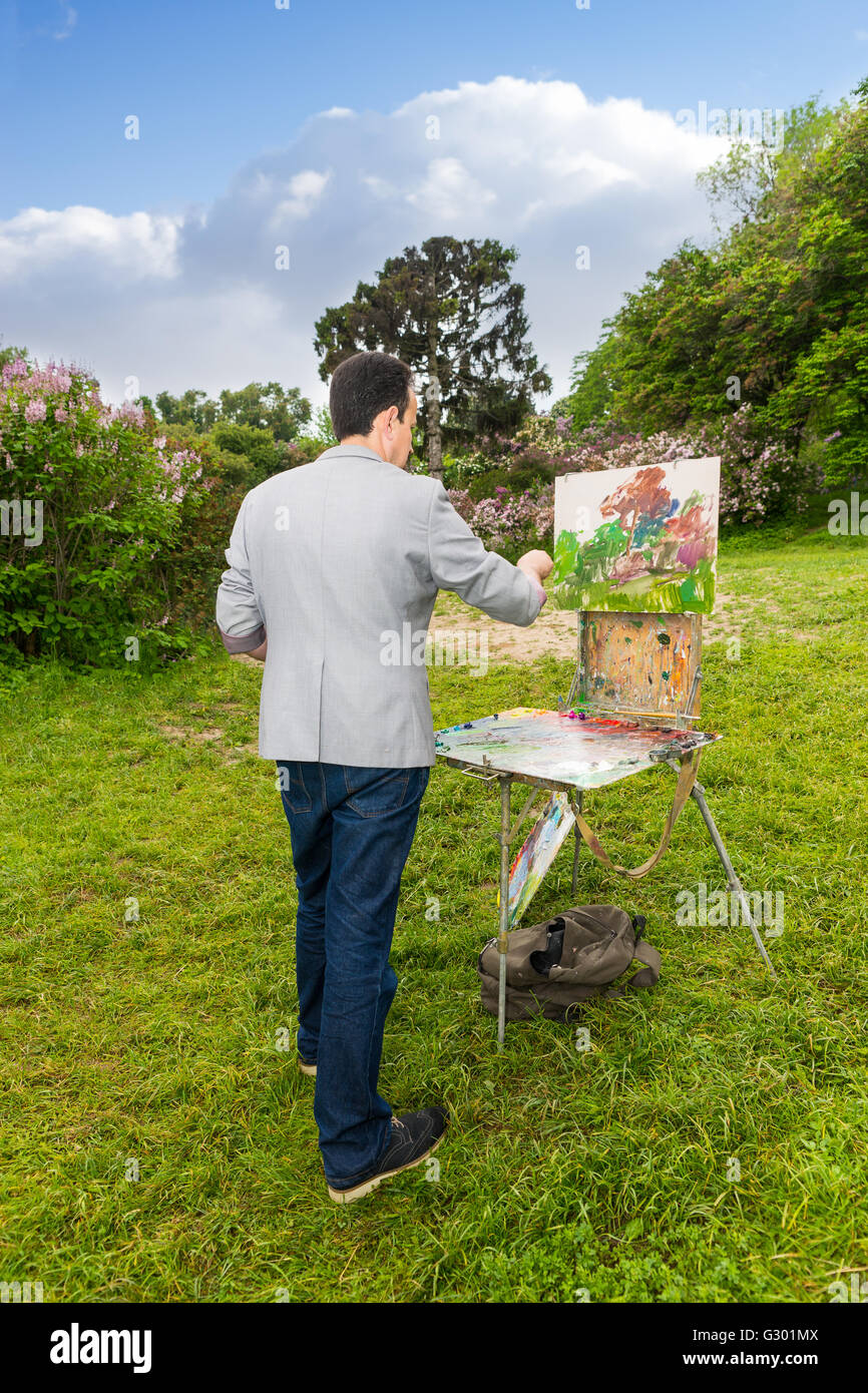 Lonely professional male artist working outdoors in the park on a ...