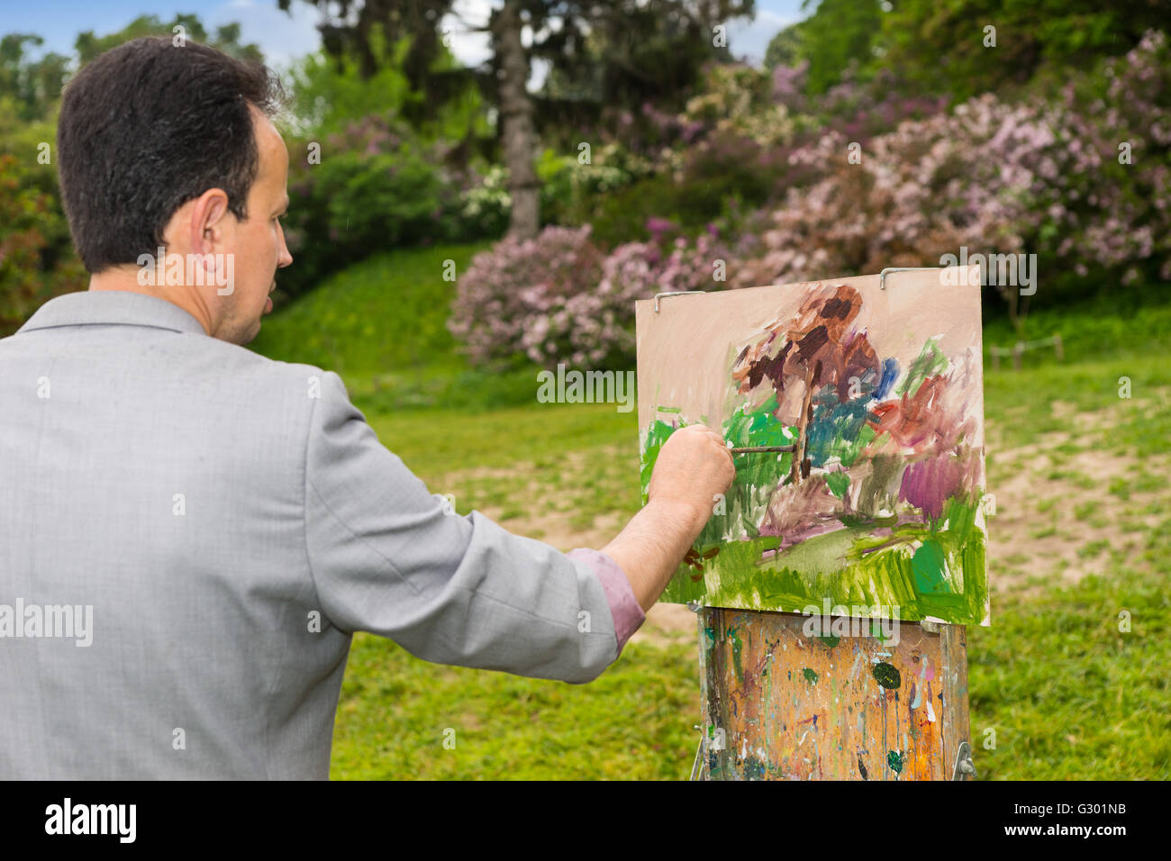 Side view of a male artist painting with oils and acrylics finishing ...
