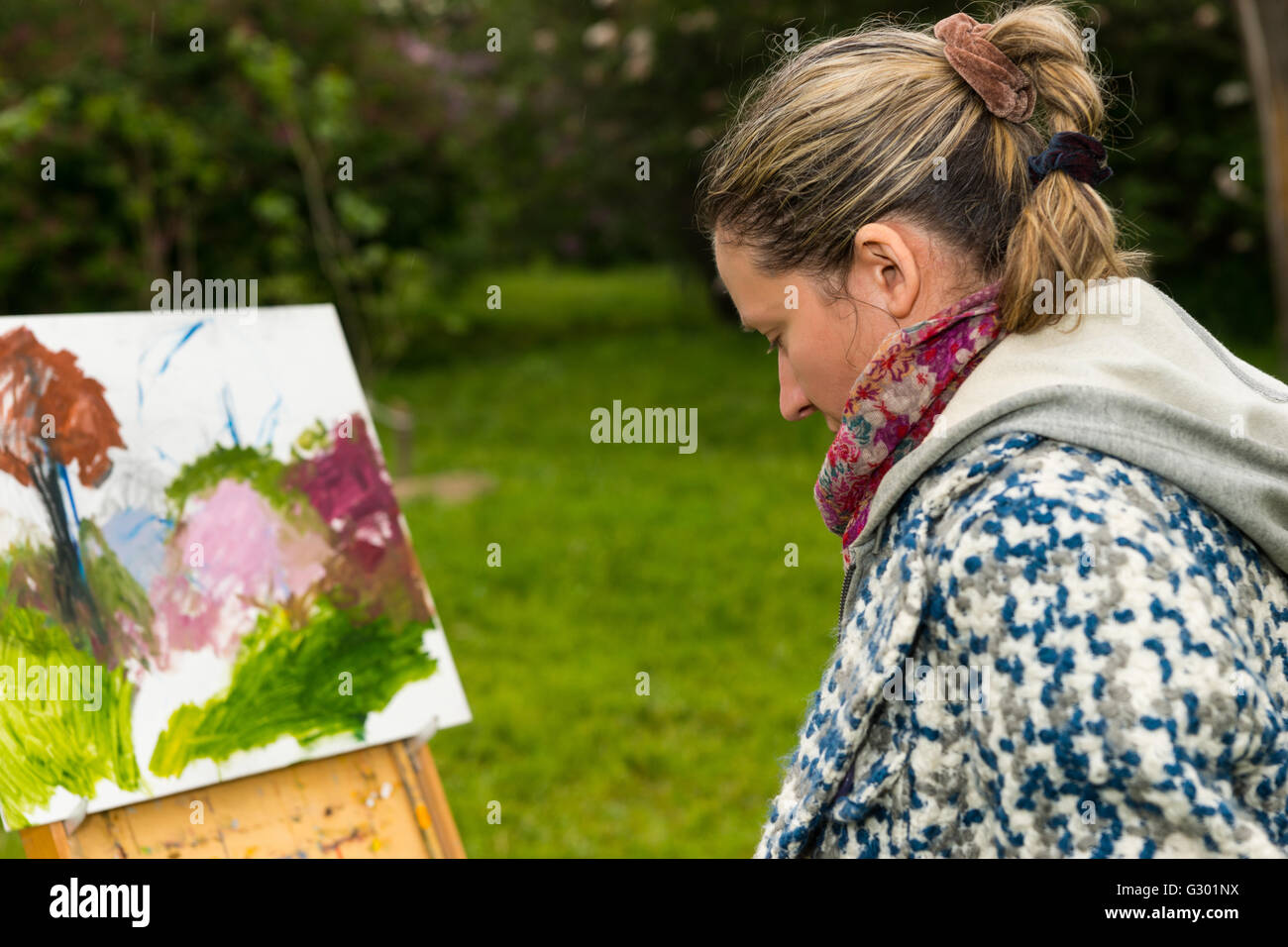 Female contemplative painter looking at her sketch on a trestle and ...