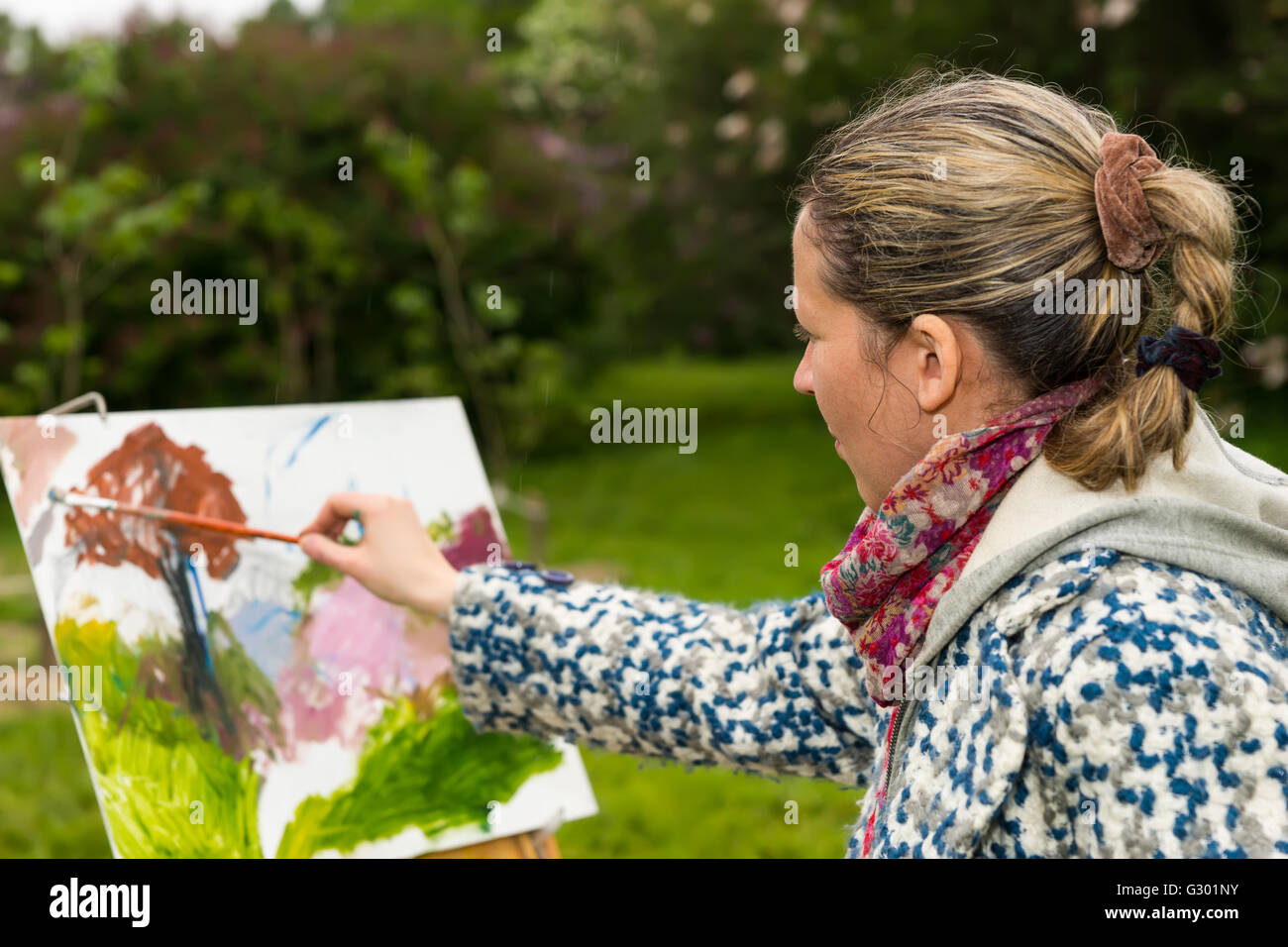 Female contemplative artist painting with oils and acrylics finishing ...