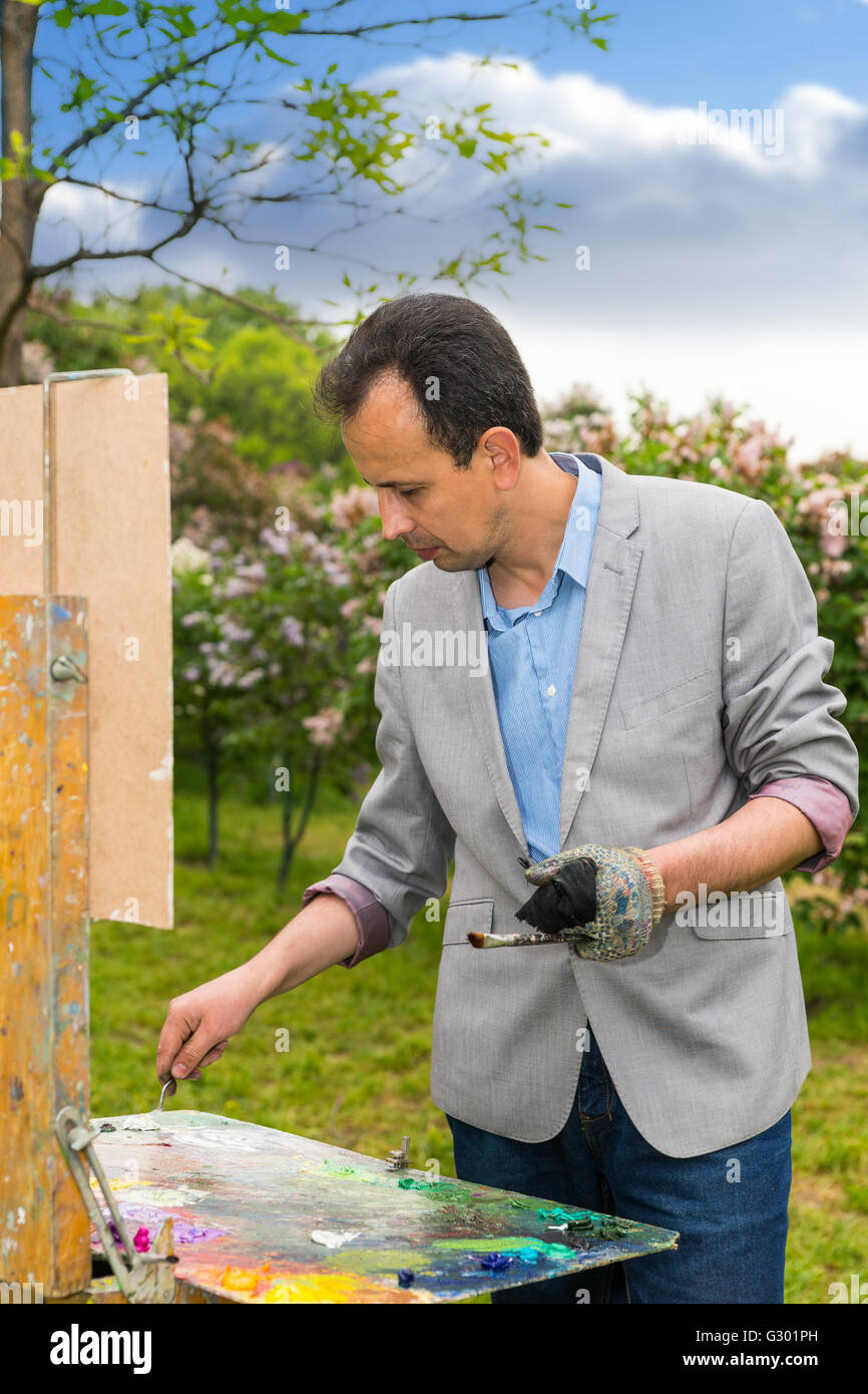 Male handsome middle-aged contemplative artist working on a trestle and ...