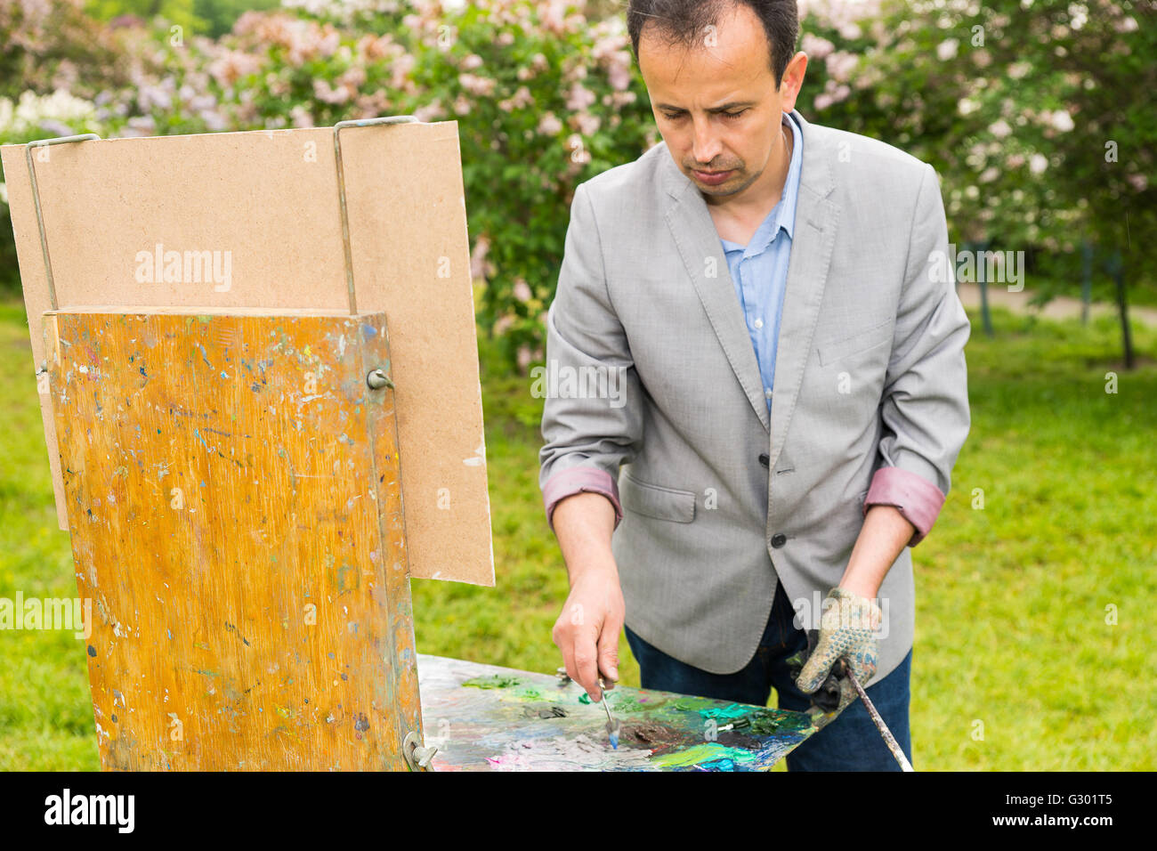 Male middle-aged concentrated creative artist working on a trestle and ...