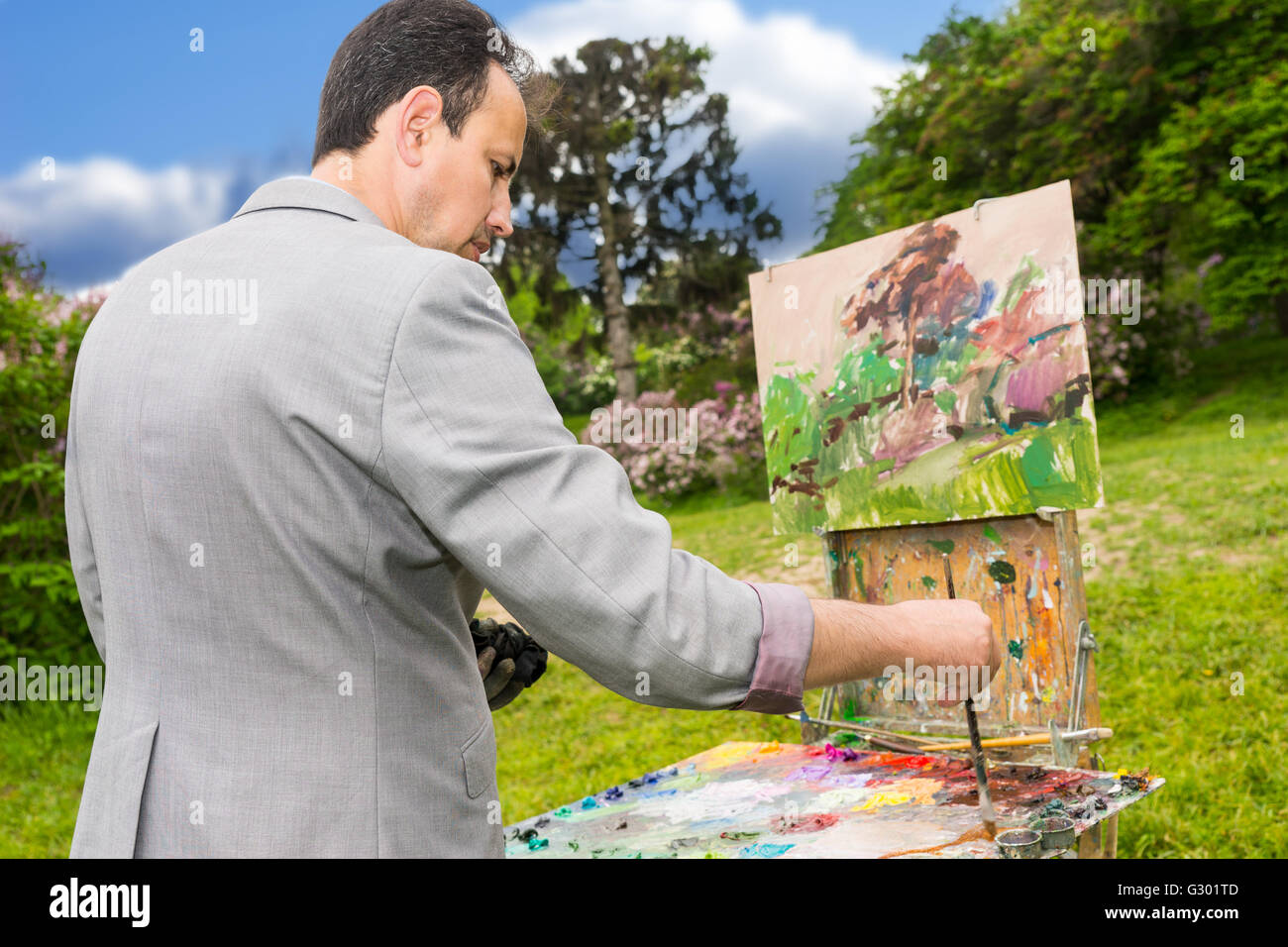 Side view of a concentrated male artist working on a trestle and easel ...