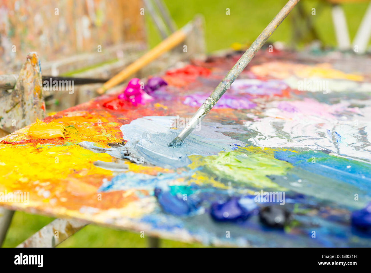 Tiny paintbrush mixing colors on the multicolored palette of blended ...