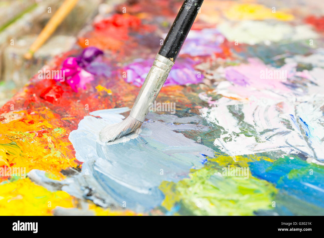 Professional paintbrush mixing colors on the multicolored palette of ...