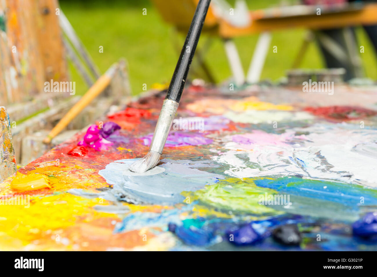 Paintbrush mixing colors on the multicolored palette of blended oil ...