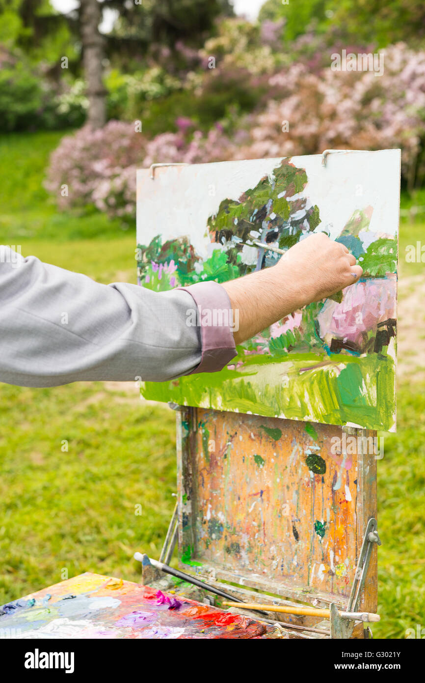 Hand of a man artist in the open air finishing his sketch of glorious ...