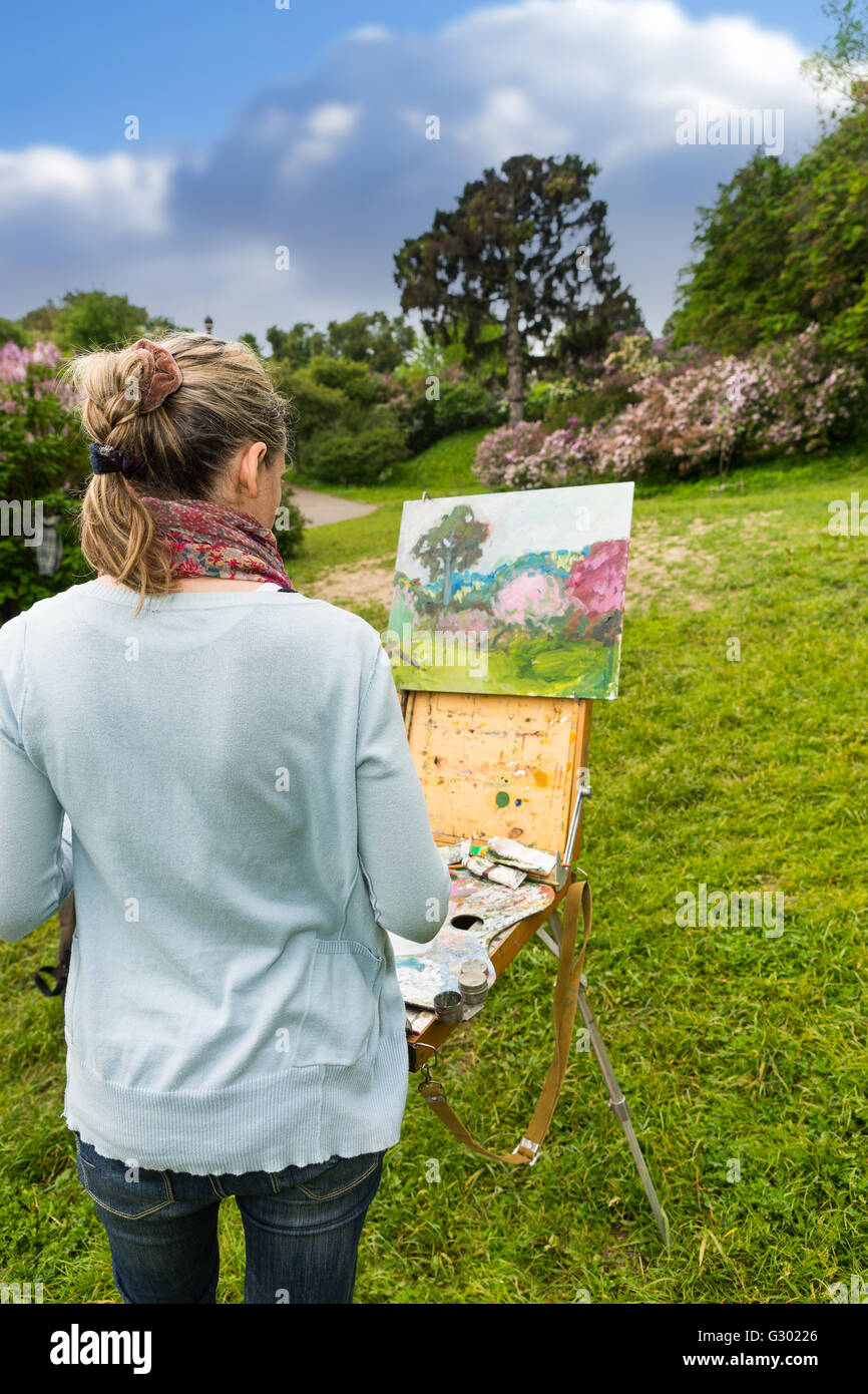 Back view of female artist looking to her picture on a sketchbook ...