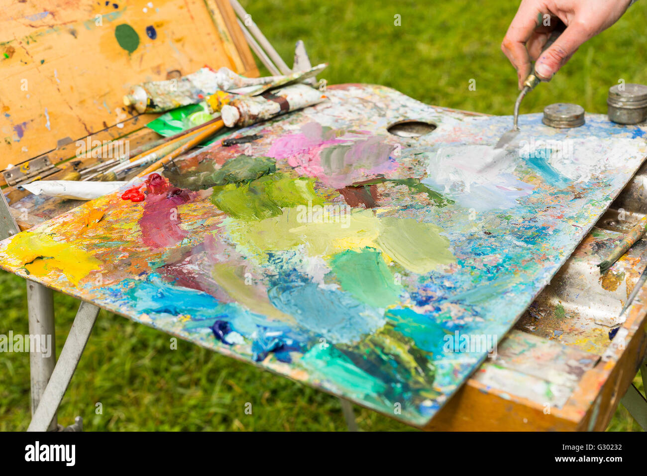 Painter's hand working with paletteknife and mixing colors on the ...