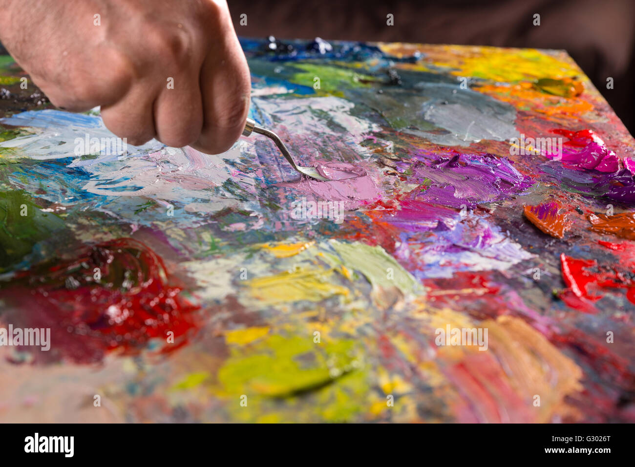 Professional palette knife mixing various bright colors on the colorful ...