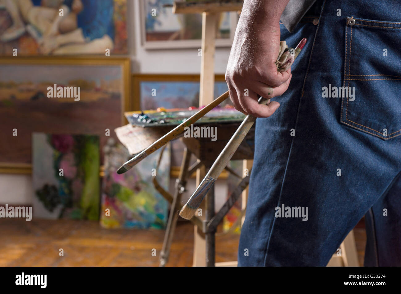 Close up on the hand of an artist with a paint brush standing in a ...