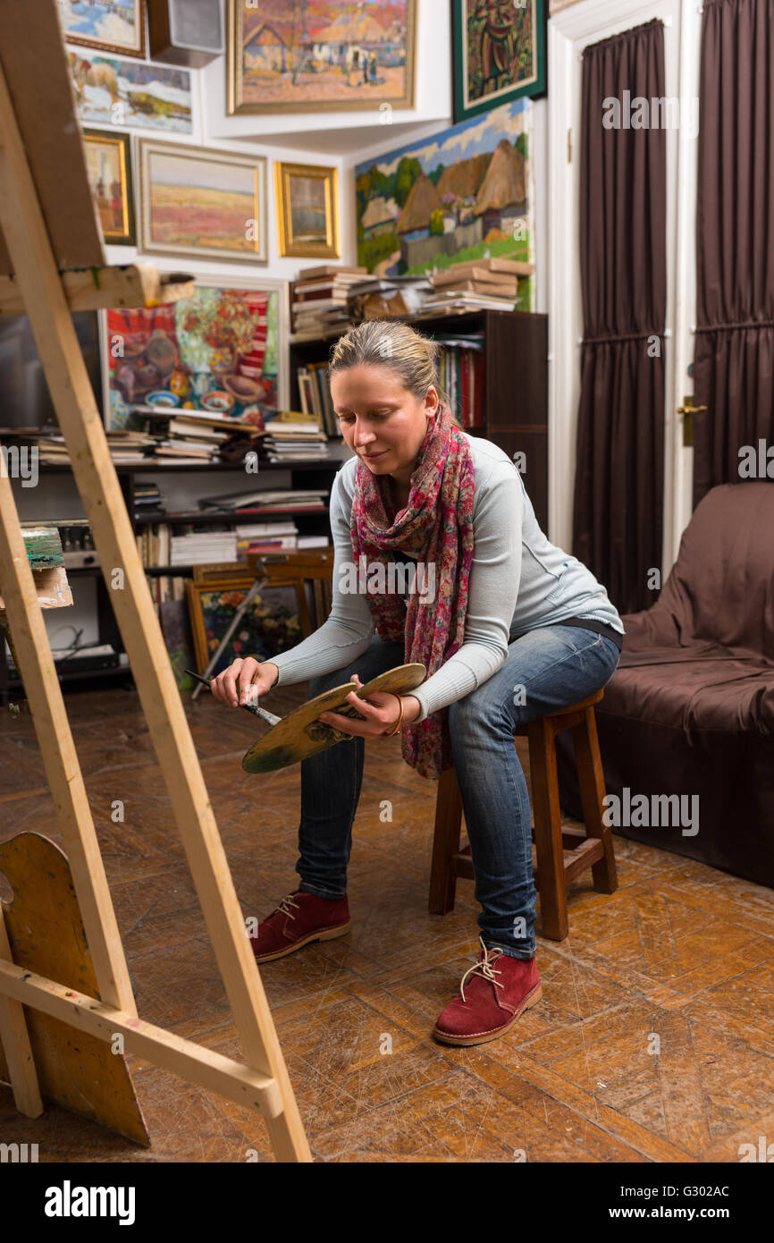 Attractive female artist sitting painting in a studio or gallery ... Attractive female artist sitting painting in a studio or gallery ...