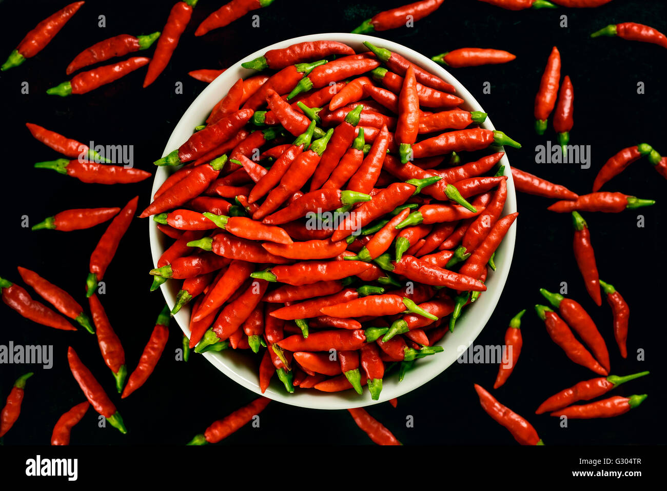 Red chilli peppers against a black background Stock Photo - Alamy