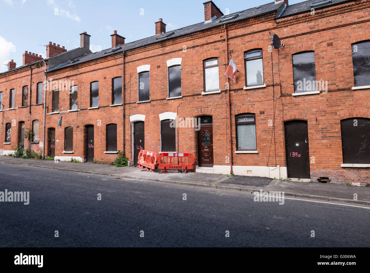A long row of derelict houses in a street boarded up with steel plates ...
