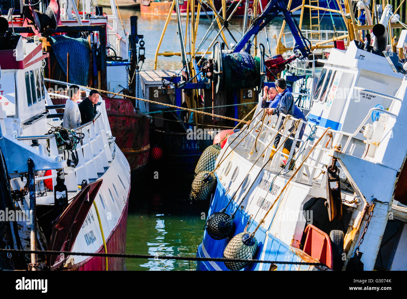 Four Filipino crewmembers have a conversation between two trawlers in a ...