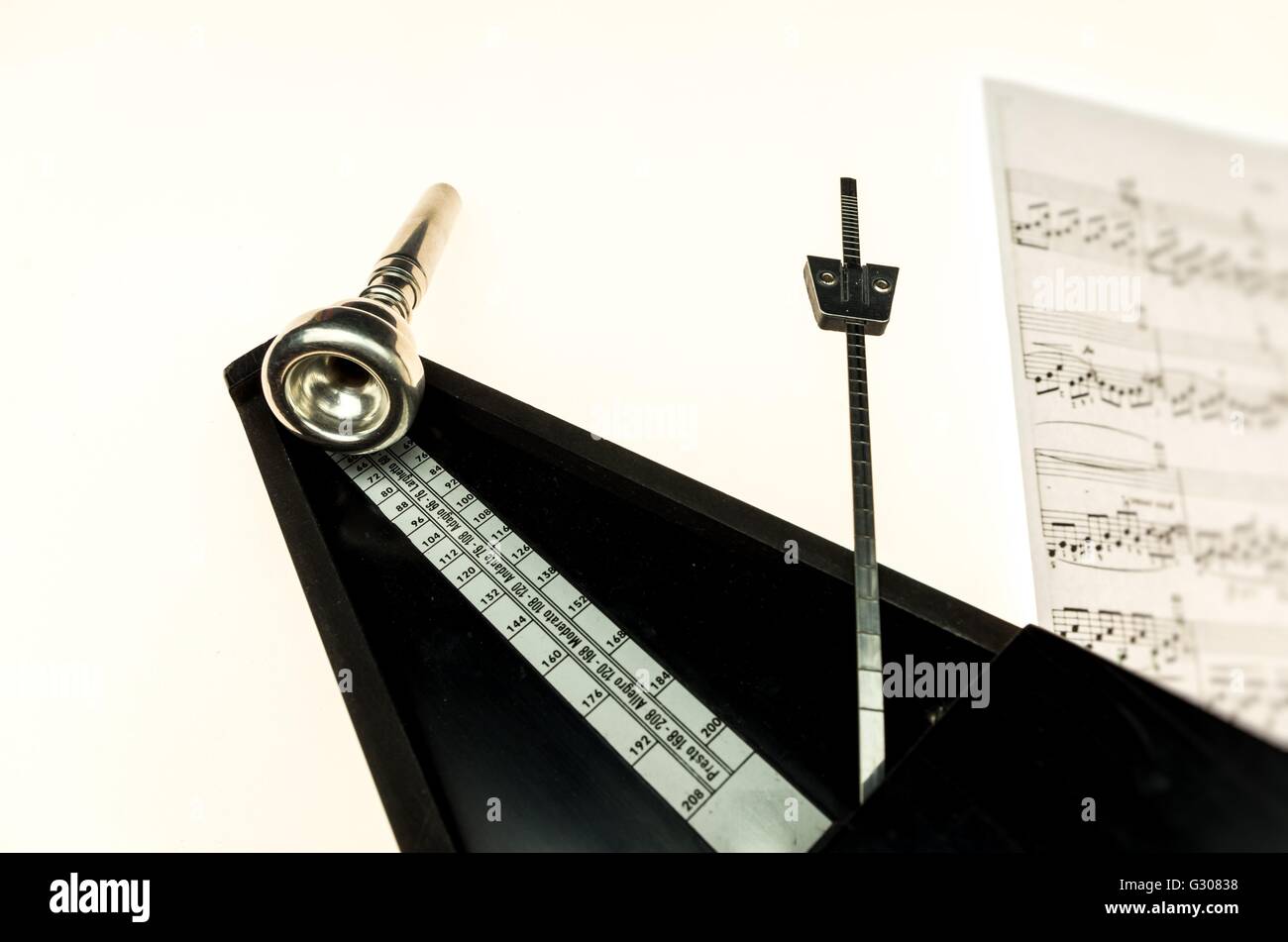 Metronome and mouthpiece of a trumpet isolated on a blank white ...