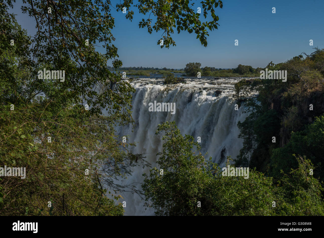 Glimpse of Victoria Falls framed by branches Stock Photo - Alamy