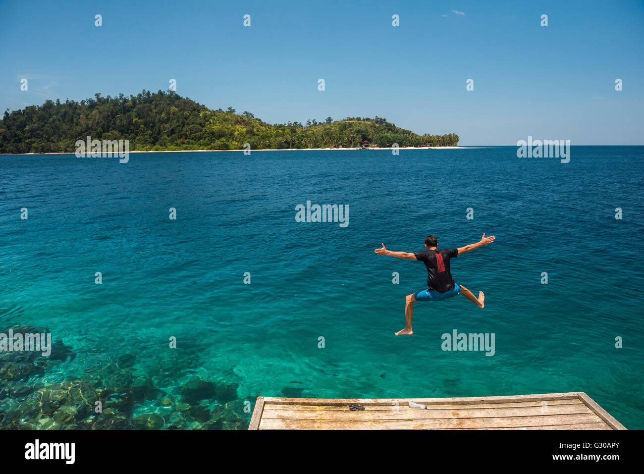 Tourist jumping into the Pacific Ocean at Twin Beach, a tropical white ...