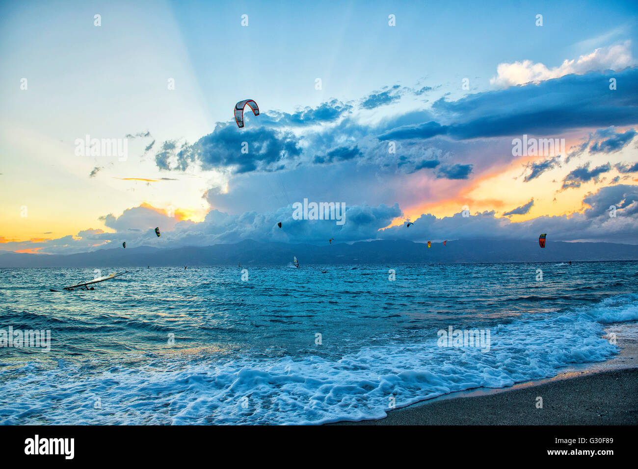 Bocale, Reggio Calabria beach. Boys go kite surfing at sunset with ...