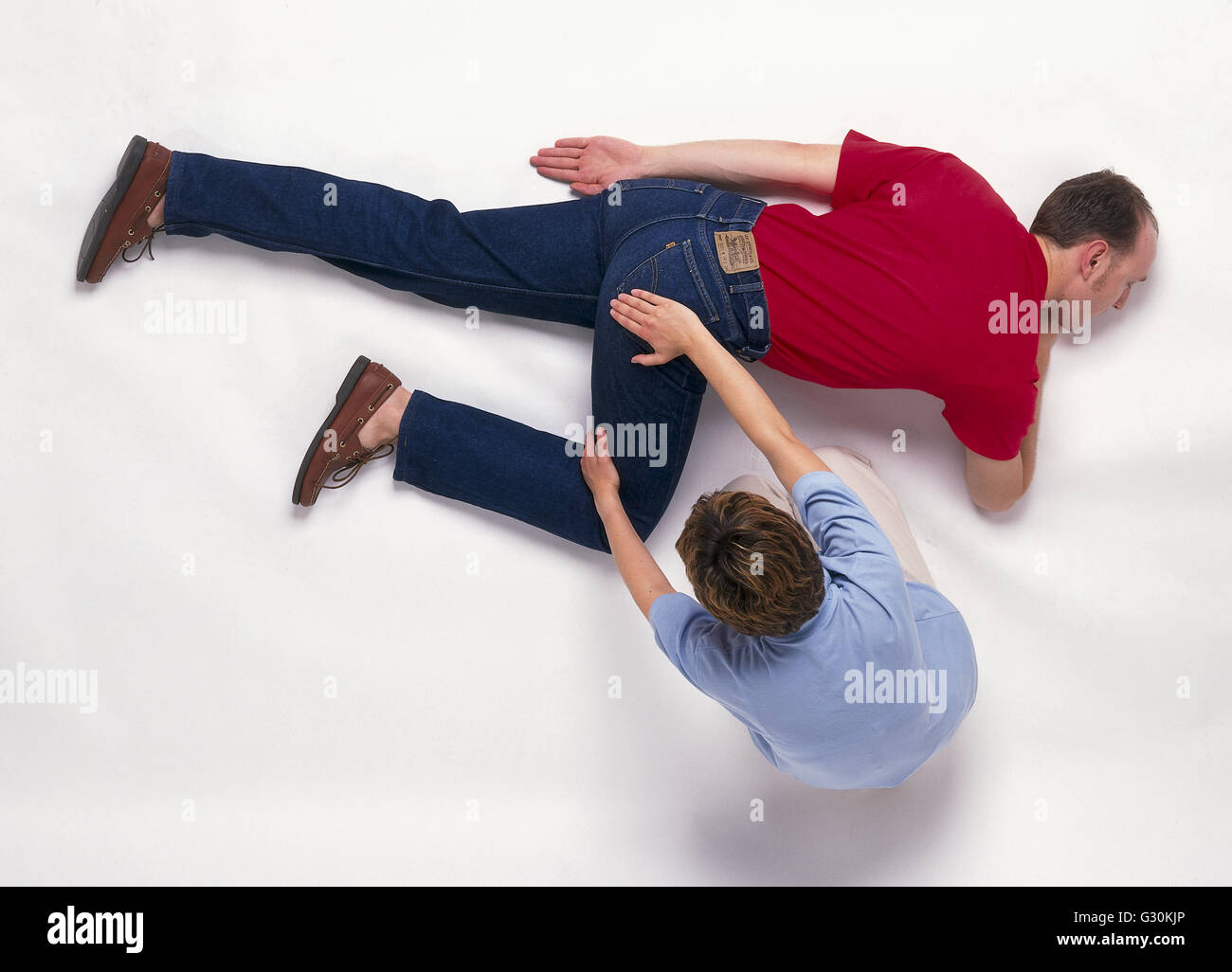 First aider pulling casualty's leg at right angles to his body to ...