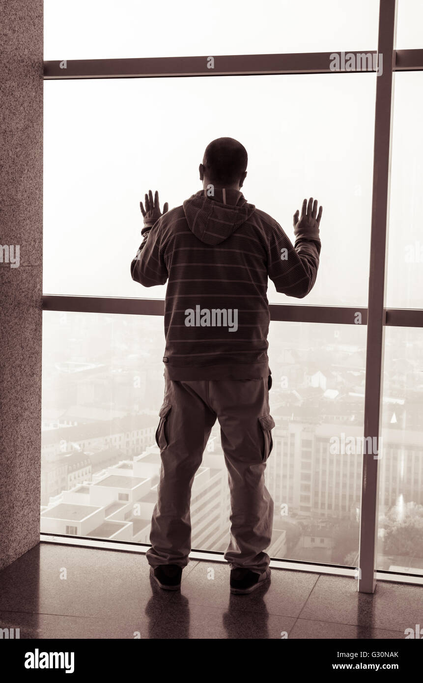 man prisoned in high building touching a window Stock Photo - Alamy
