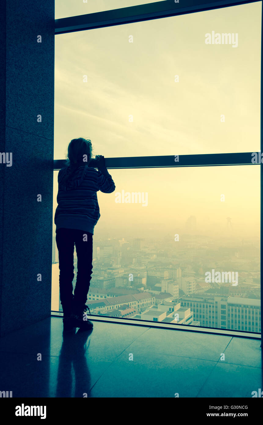 little child looking through a window to the city Stock Photo - Alamy