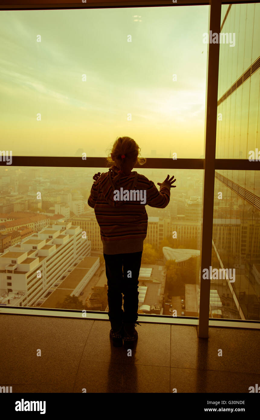 little child looking through a window to the city Stock Photo - Alamy