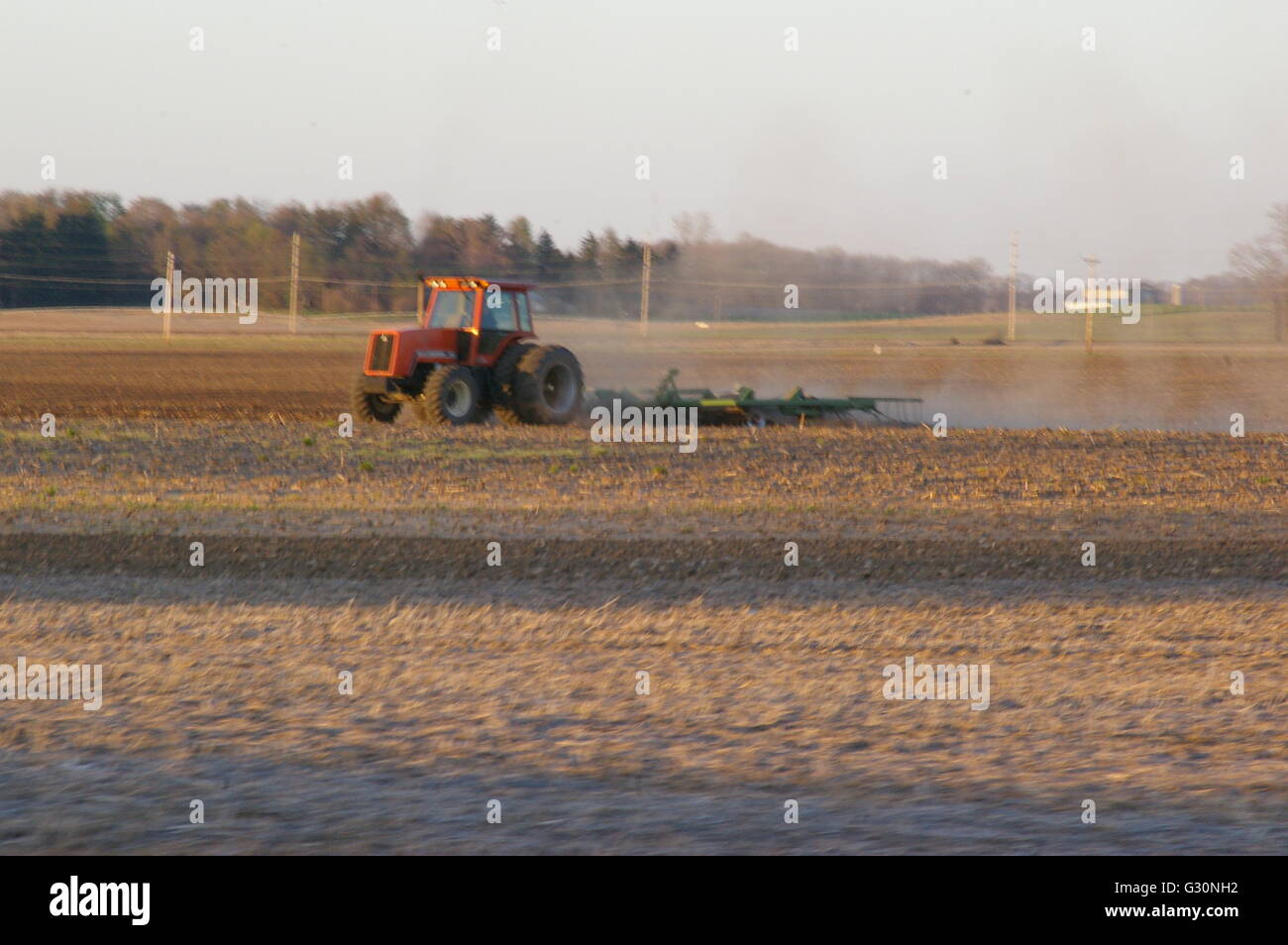 Red Tractor Pulling Machine Tills An Empty Field Stock Photo - Alamy