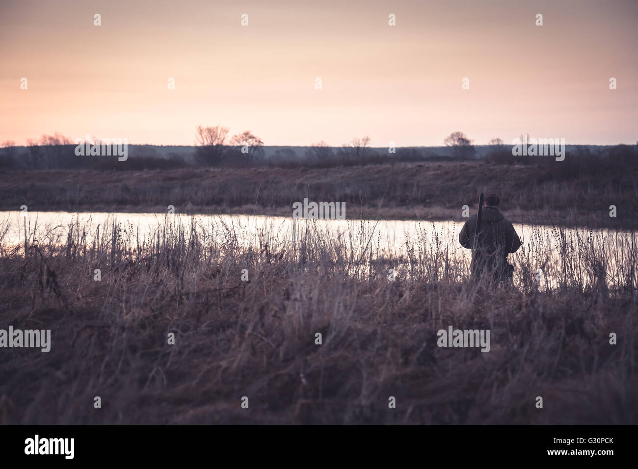 Hunter man in rural field in expectation of hunting during sunrise with ...