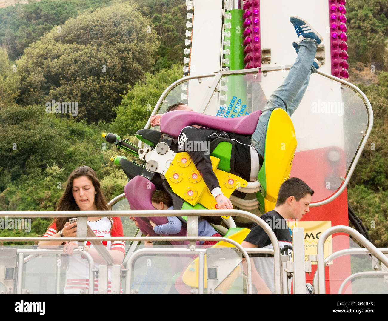 Inverted fairground riders fly pass the staff in charge. They've seen ...