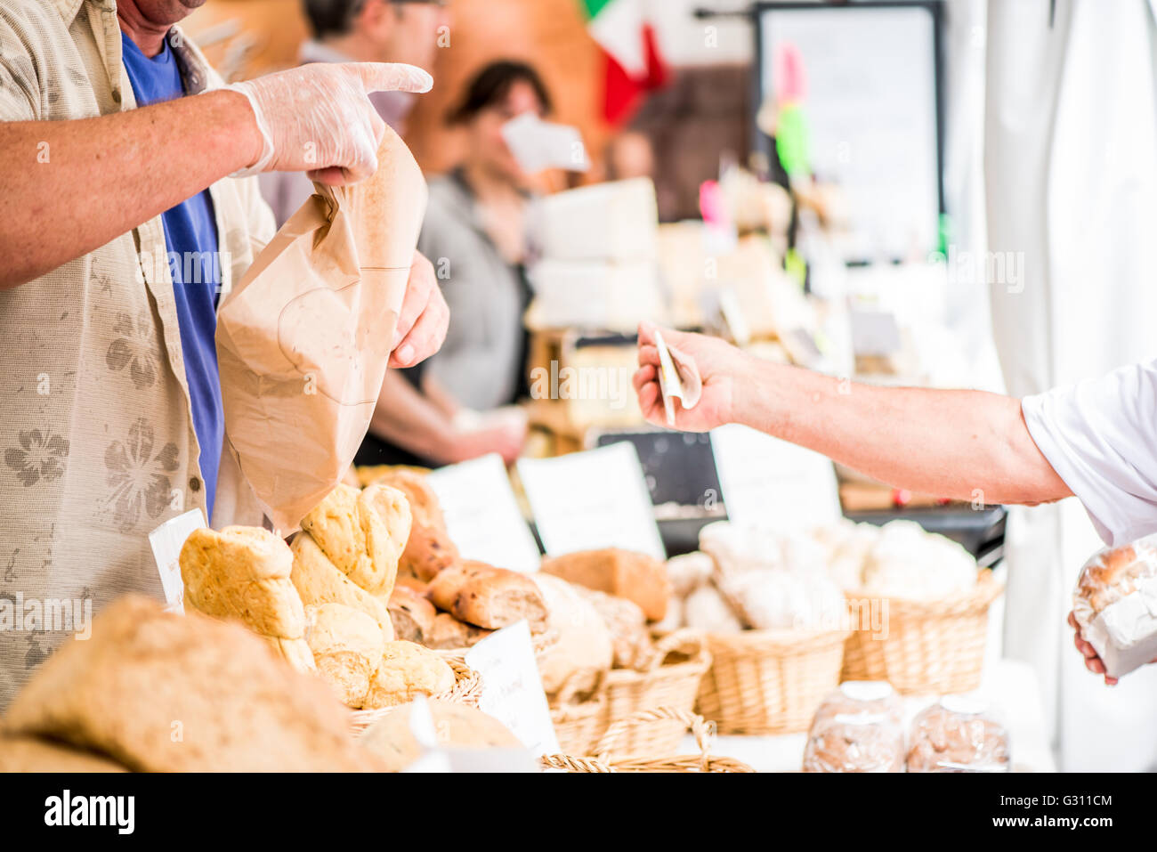 man sells bread at market stall while woman pay for shopping Stock ...