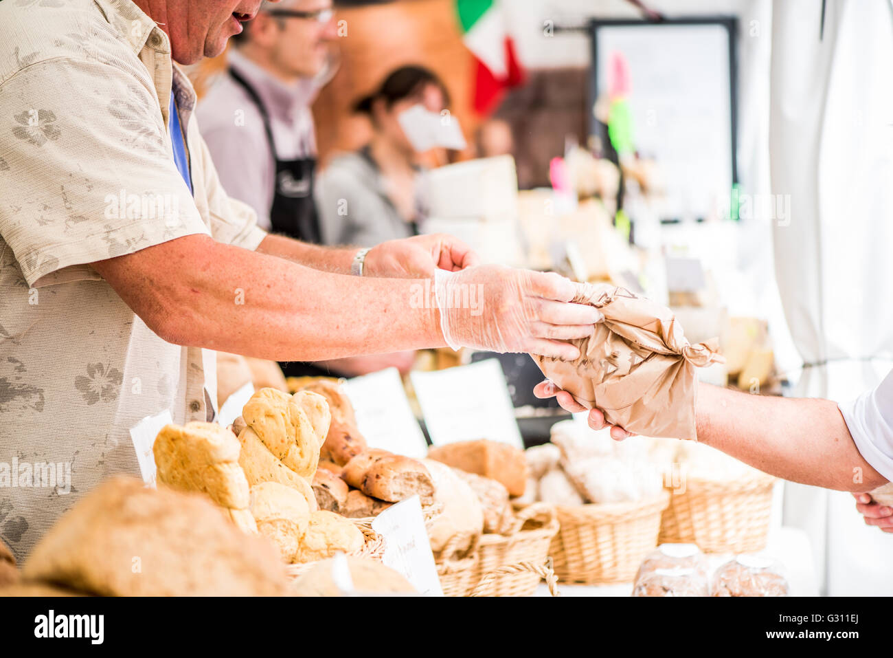 man sells bread at market stall while woman pay for shopping Stock ...