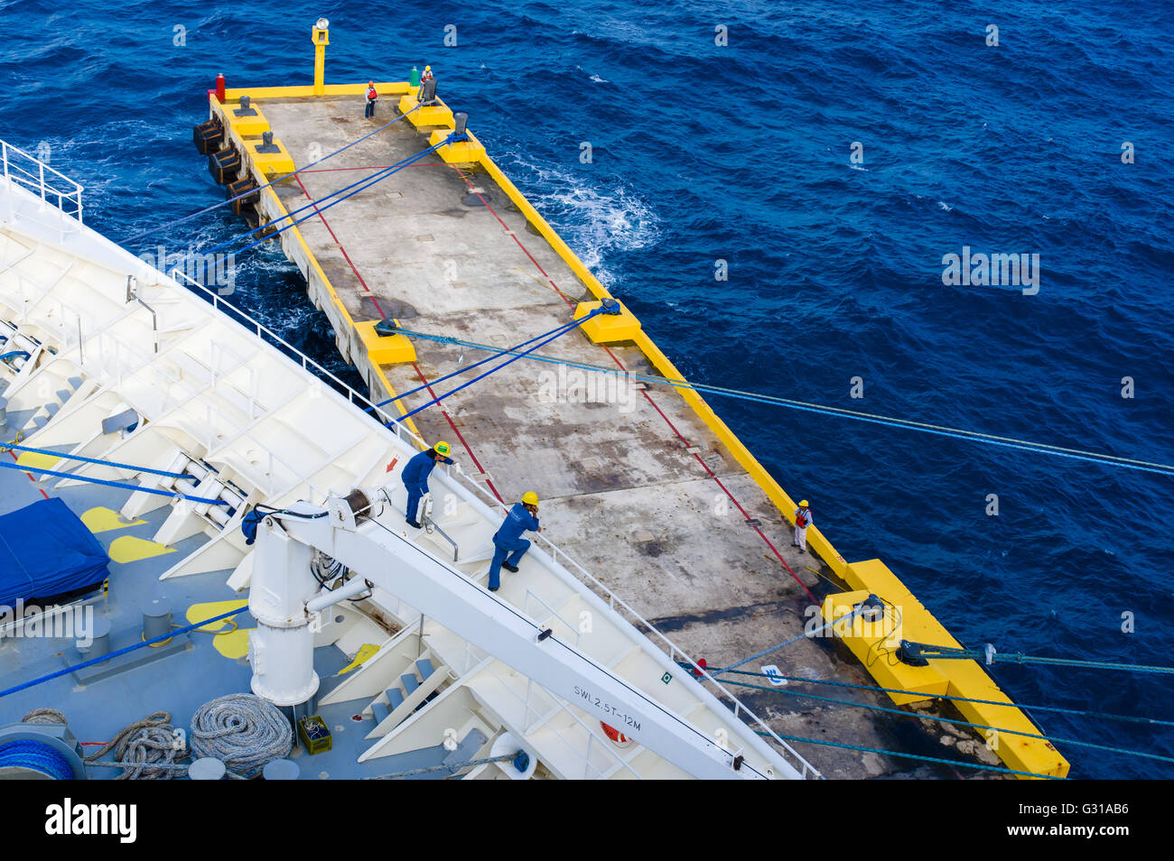 Crew members pull in the ropes securing cruise ship Vision of the Seas ...
