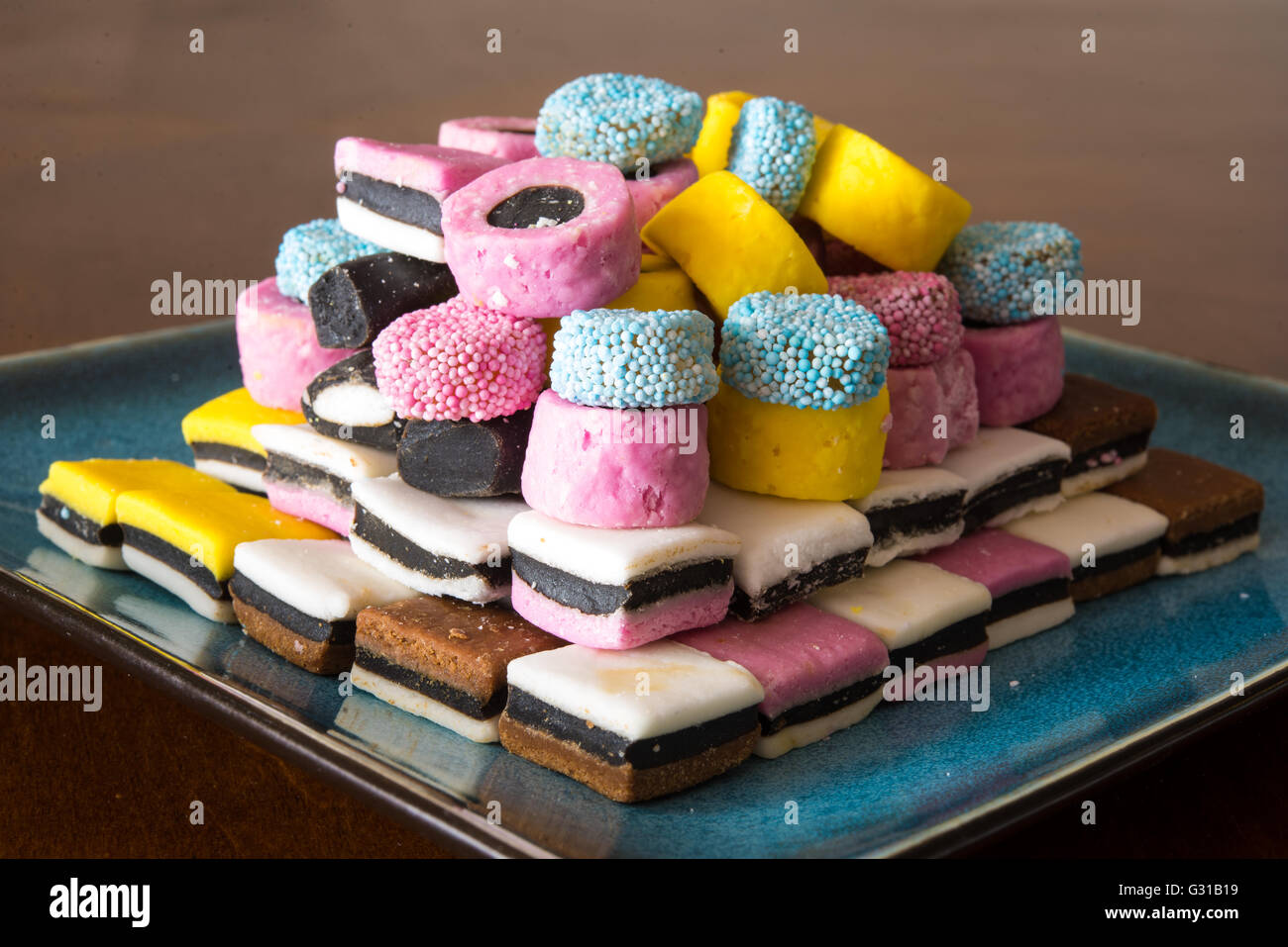 Colorful candy, blue, pink, yellow, white, brown on top of a shiny blue ...