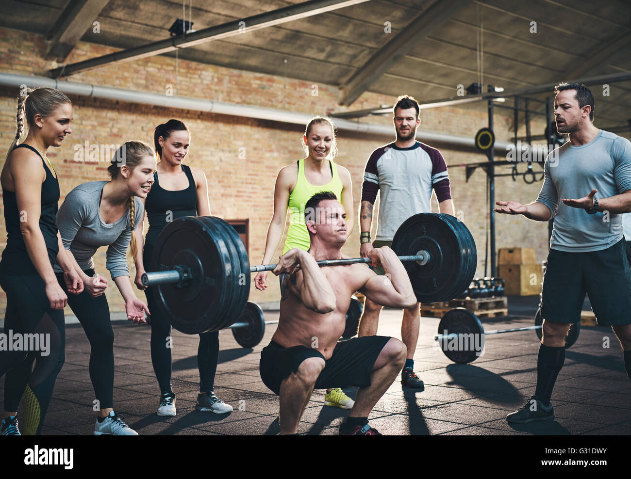 Fit man lifting barbells looking focused, working out in a gym with ...