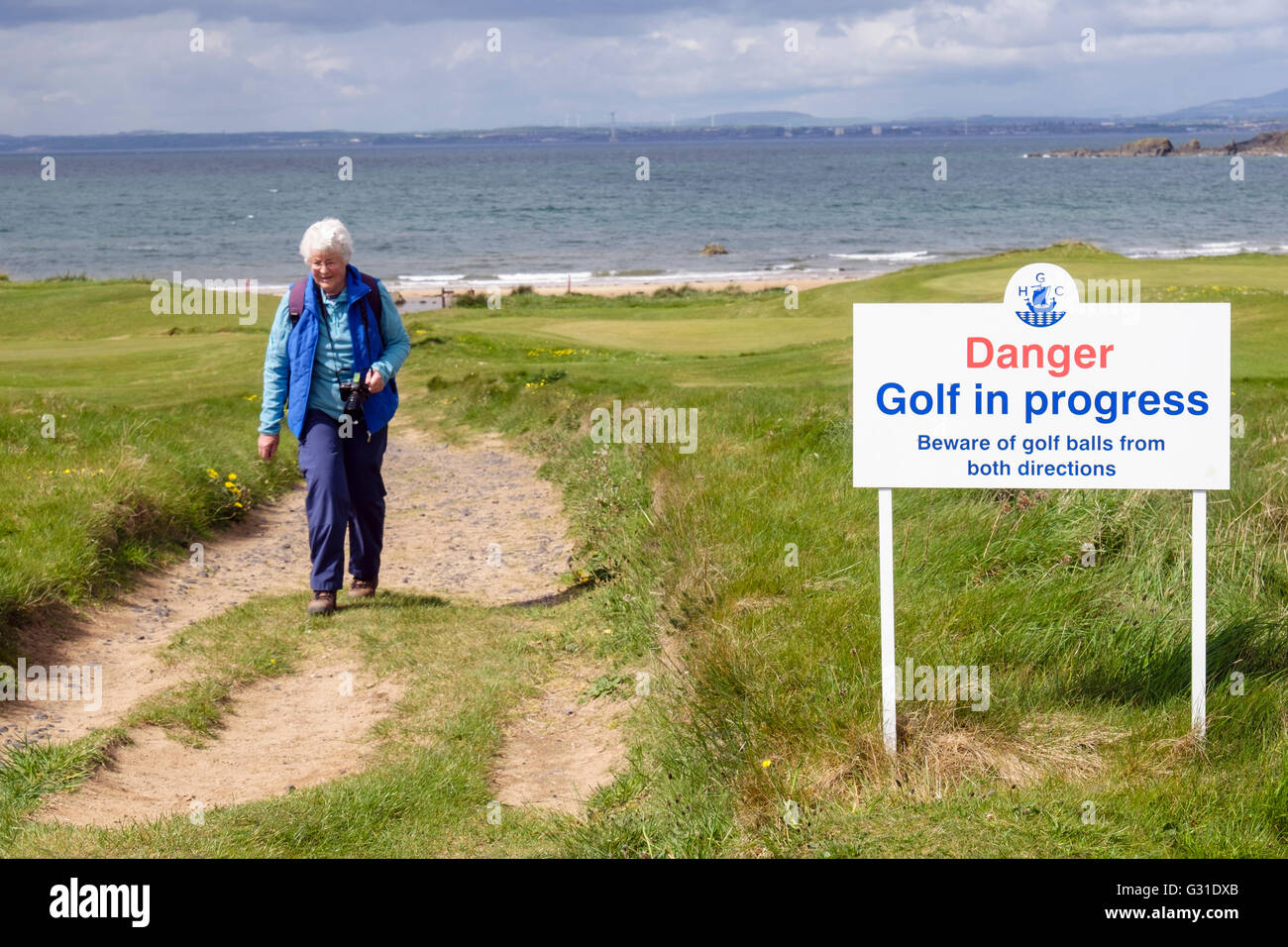 Senior woman walking on Fife Coastal Path with danger sign by ...