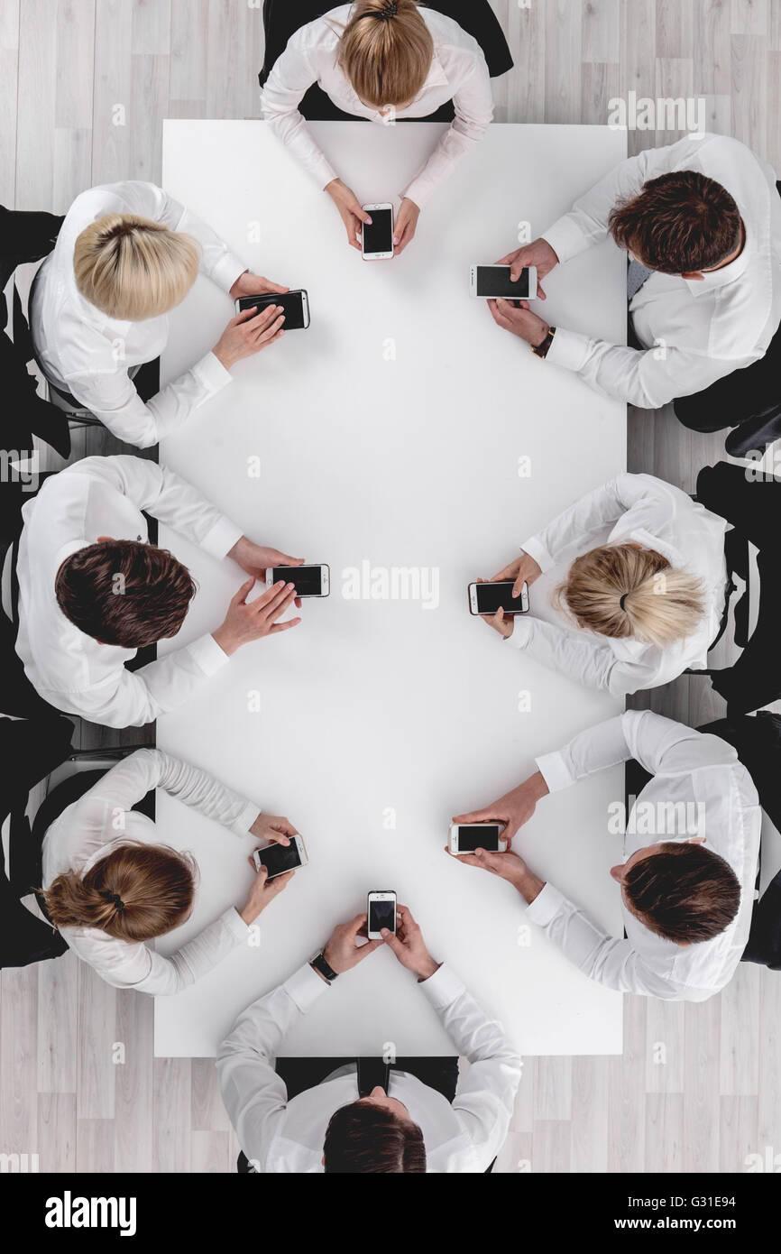 Business people sitting around the table with cell phones Stock Photo ...