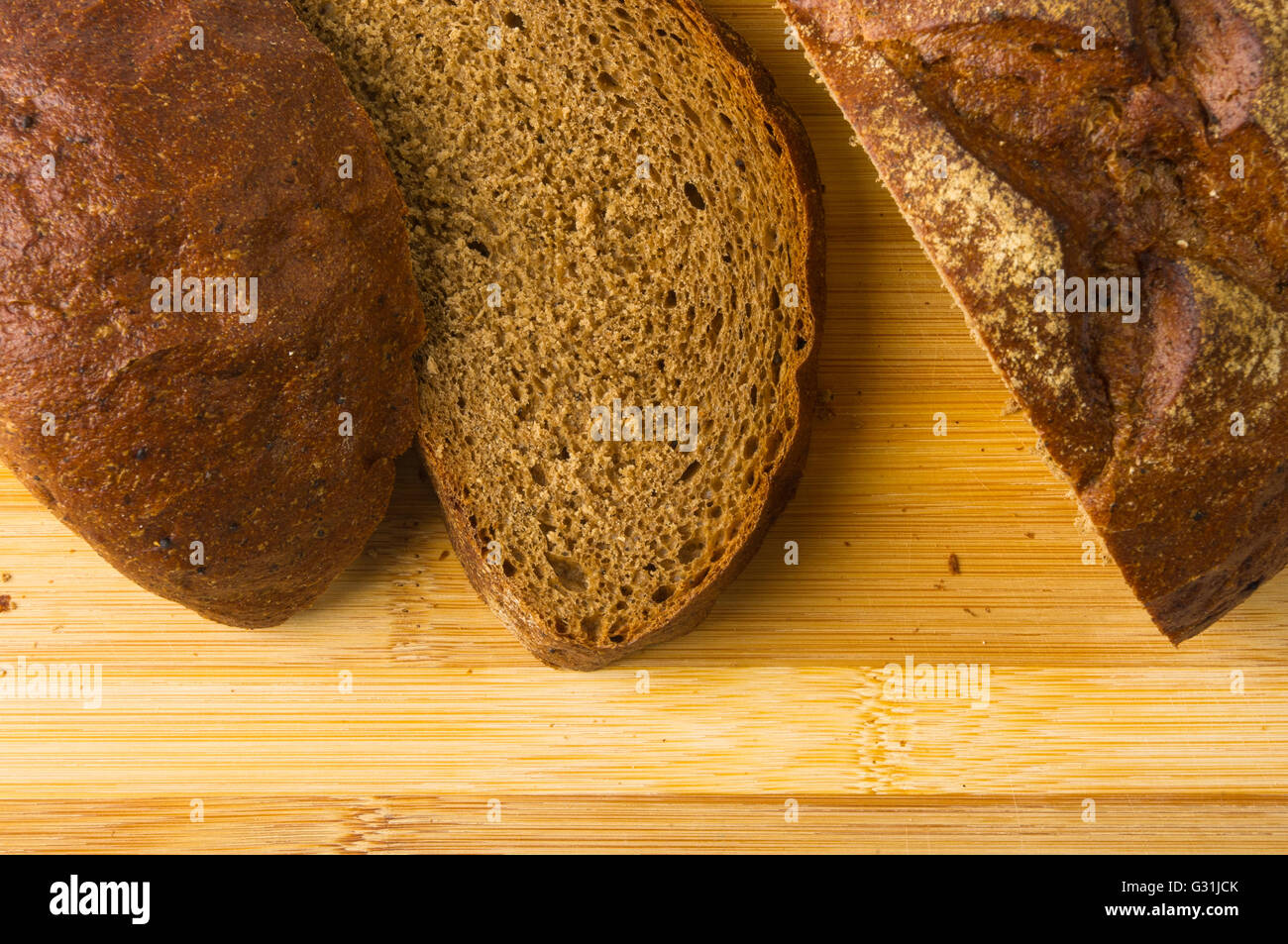 Sliced dark bread with crumbs on wood board Stock Photo - Alamy