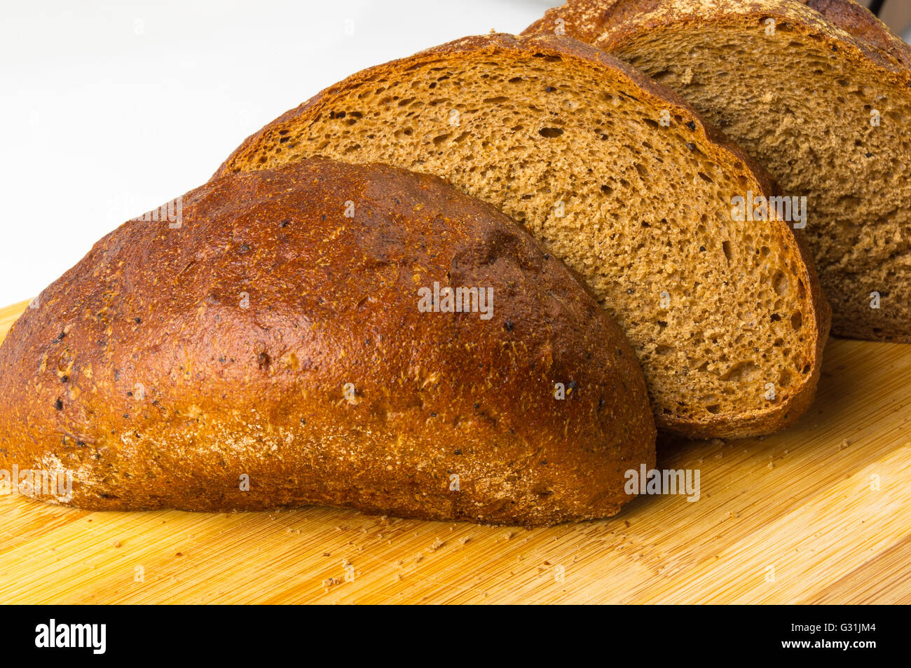Sliced dark bread with crumbs on wood board Stock Photo - Alamy
