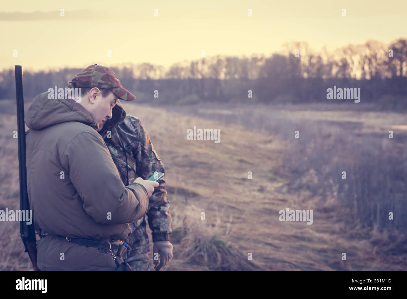 Hunters in rural field during hunting season holding smart phone Stock ...