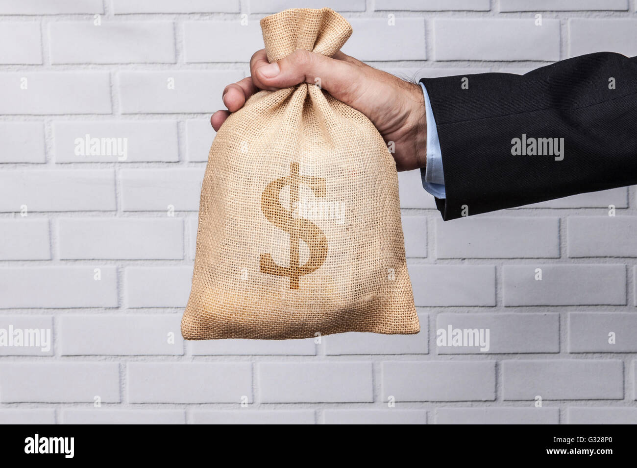 Hand holding a sack of money and white brick background Stock Photo - Alamy