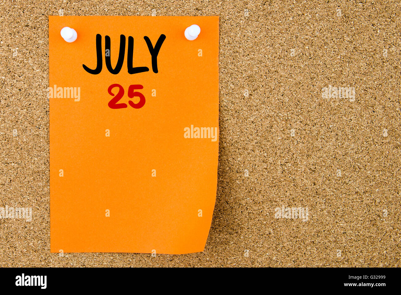 25 JULY written on orange paper note pinned on cork board with white ...