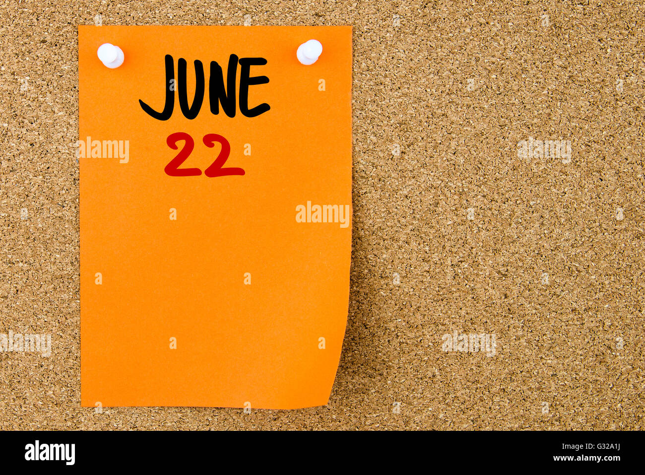 22 JUNE written on orange paper note pinned on cork board with white ...