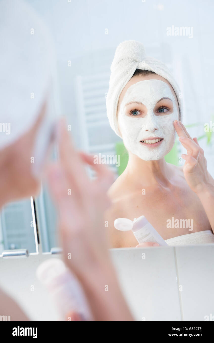 Woman, 30+, in the bathroom applying a facial mask Stock Photo - Alamy