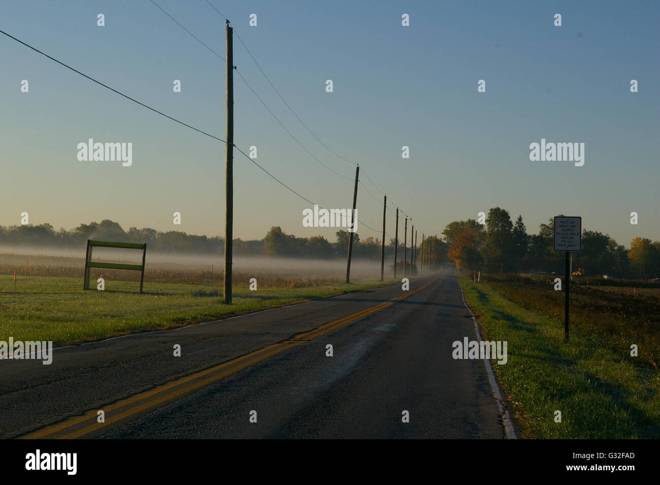 Fog On A Corn Field With Road And Telephone Poles At Dawn With Blue Sky ...