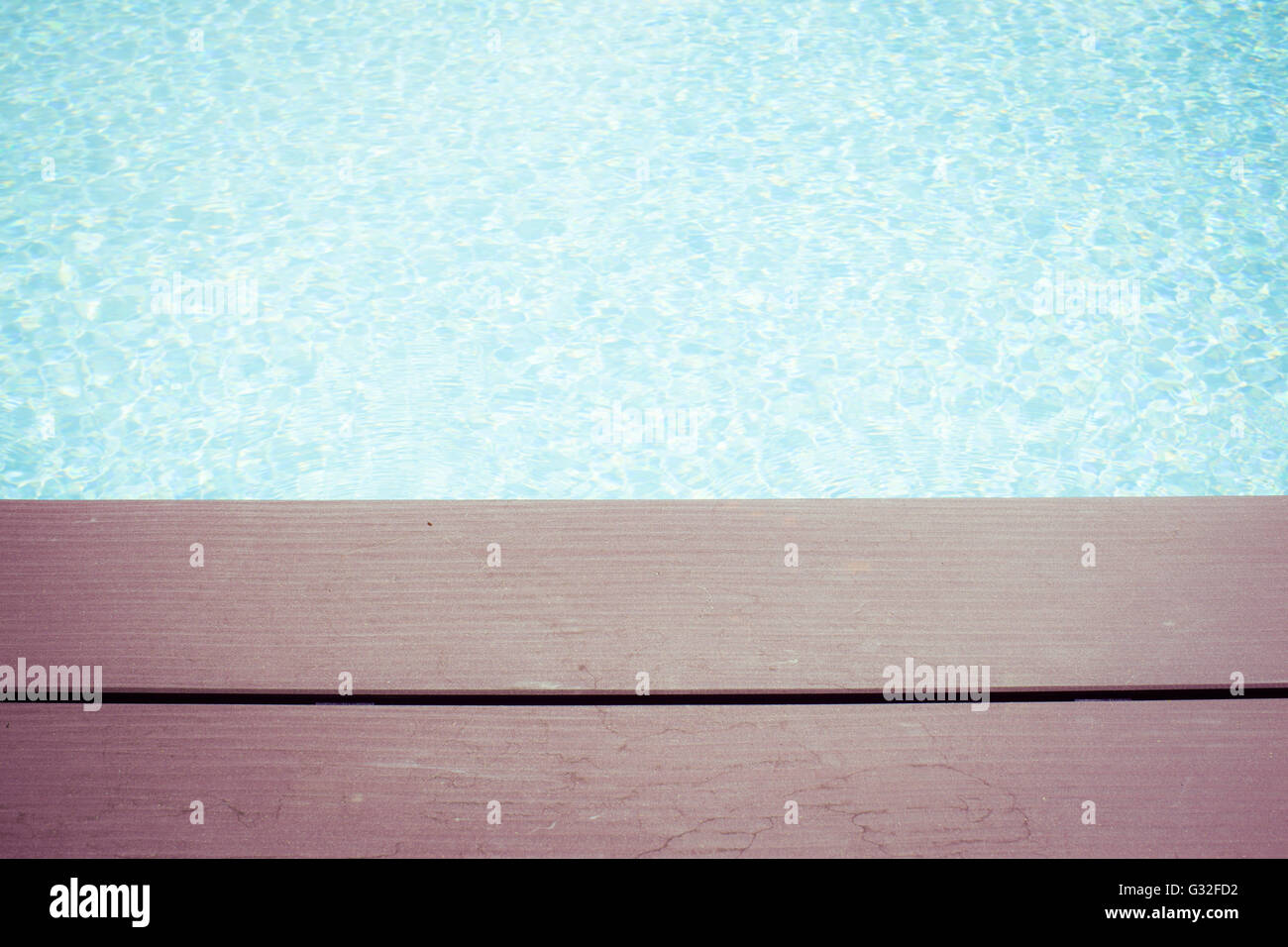 wooden planks at the pool side with vibrant pool water and a vintage ...