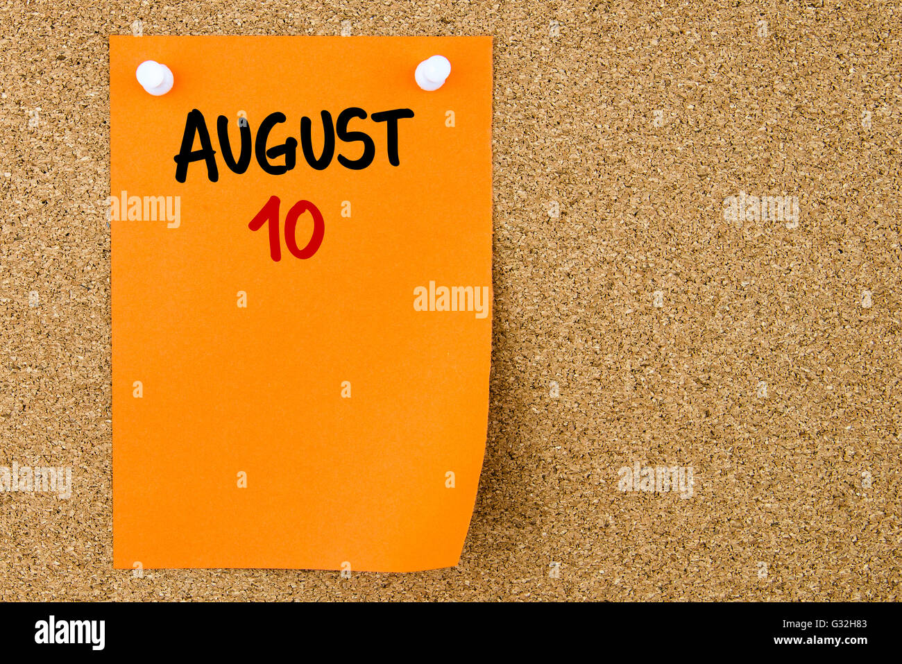 10 AUGUST written on orange paper note pinned on cork board with white ...