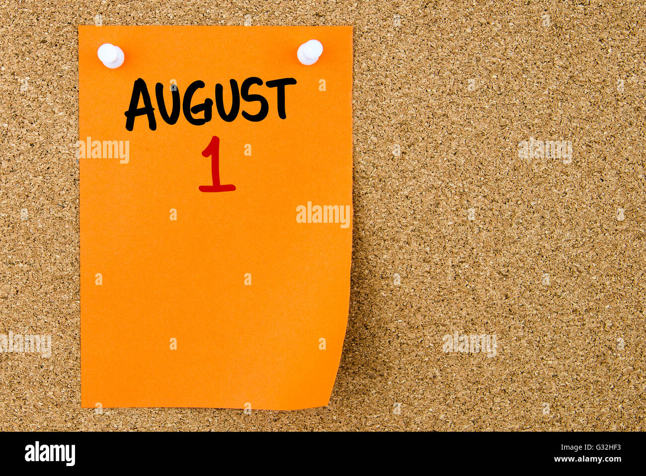 1 AUGUST written on orange paper note pinned on cork board with white ...