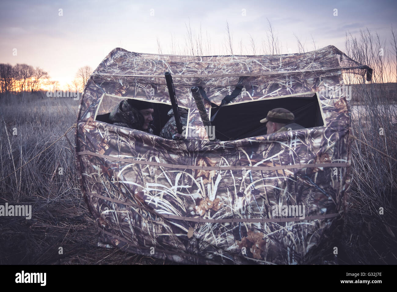 Hunting tent with hunters waiting for prey in reed bushes next to the ...