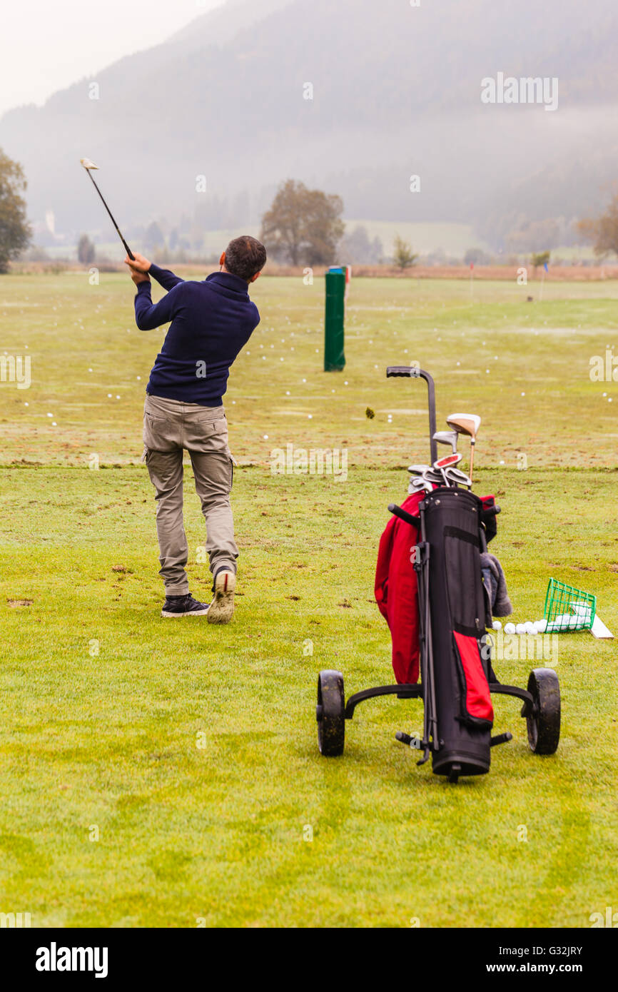 a golf player practicing the swing on the driving range Stock Photo - Alamy